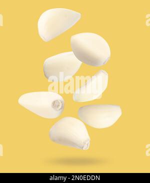 Many garlic cloves falling on yellow background Stock Photo - Alamy