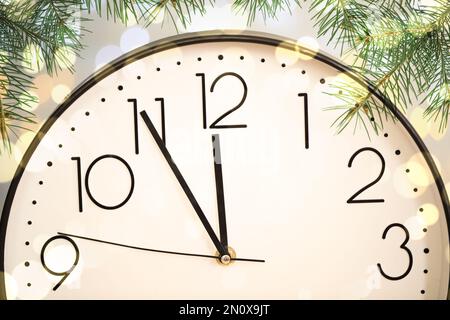 Clock showing five minutes till midnight with fir tree branches ...