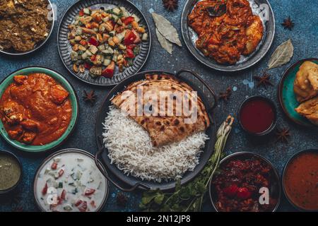 Indian ethnic food buffet on concrete table from above: curry, samosa ...