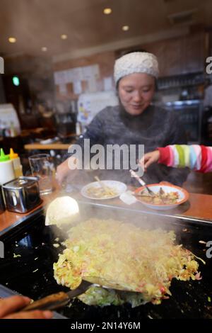 A Japanese woman cooking Okonomiyaki on a teppan Stock Photo - Alamy