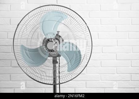 Electric fan near white brick wall, closeup. Summer heat Stock Photo ...