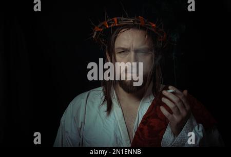 Jesus Christ smokes a cigarette wearing a crown of thorns and white ...