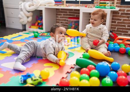 Adorable hispanic baby playing with balls lying on floor at ...