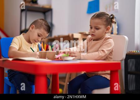 Two kids preschool students sitting on table drawing on paper at ...