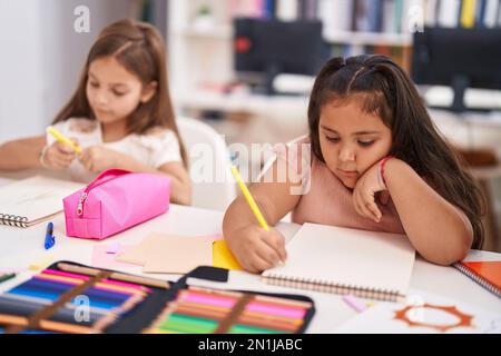 Two kids preschool students sitting on table drawing on paper at ...