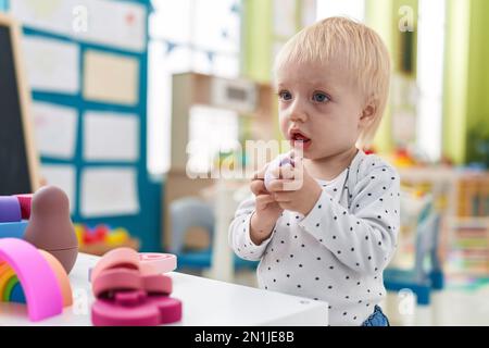 Adorable blond toddler playing with toys standing at kindergarten Stock ...