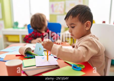 Two kids preschool students sitting on table drawing on paper at ...