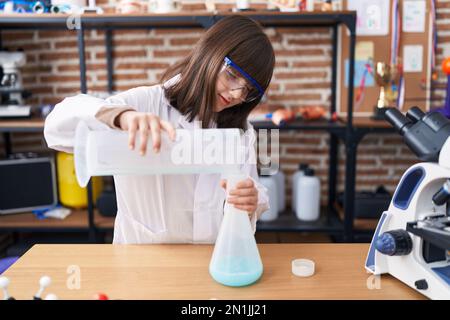 Adorable toddler student pouring liquid on test tube at classroom Stock ...
