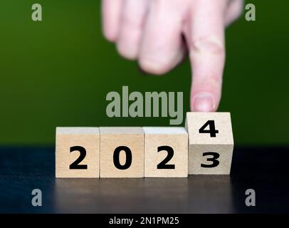 Planning 2024 changes new year symbol. Businessman turns a wooden cube ...