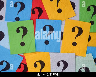 Pile of colorful paper notes with question marks on green grass. Close ...