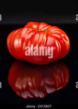 Large red heirloom tomatoe on black tabletop Stock Photo - Alamy