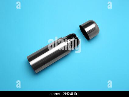 Stainless steel thermos on light blue background, top view. Space for ...