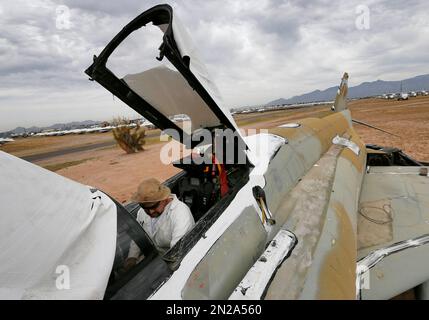 A demilitarization crew member removes components from the cockpit of ...