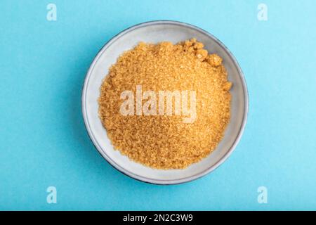 plate with unrefined golden cane sugar on blue pastel background. top ...