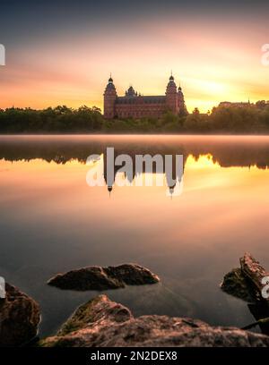 Johannisburg Castle reflected in the Main, riverbank, dawn twilight ...