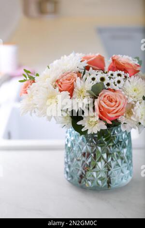 Vase with beautiful flowers on countertop in kitchen, space for text ...