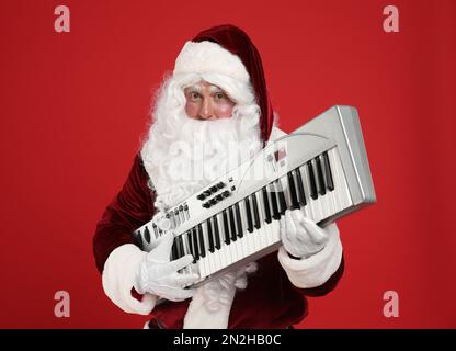 Santa Claus with synthesizer on red background. Christmas music Stock ...