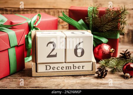 Block calendar with Boxing Day date, alarm clock and gifts on wooden ...