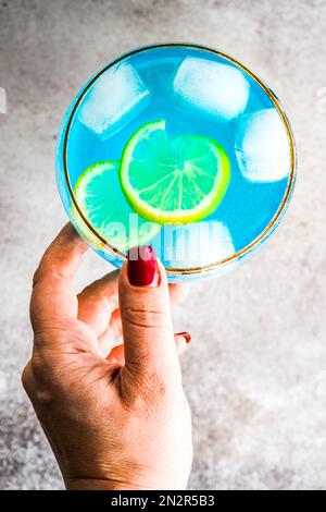 Close-up of a woman reaching for a vodka cocktail and a tumbler filled ...