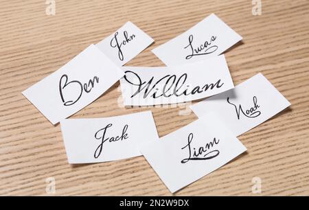 Paper sheets with written baby names on wooden table, flat lay Stock ...
