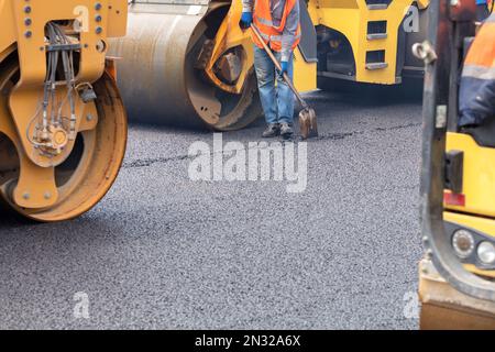 Worker uses tool to level freshly poured concrete at construction site ...