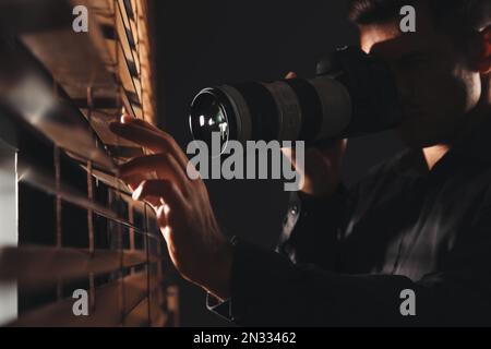 Private detective with camera spying near window indoors Stock Photo ...