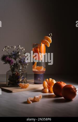 a purple glass of water and clementine skin in it, some fresh fruit ...