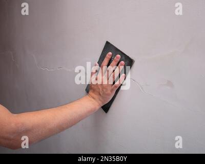 White Man Repairs White Wall Using Sandpaper Stock Photo - Alamy