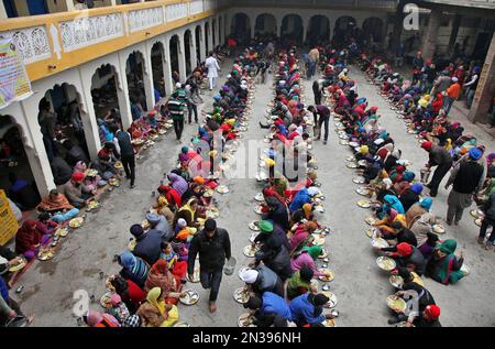 Sikh devotees eat a meal from a community kitchen at a gurudwara, or ...