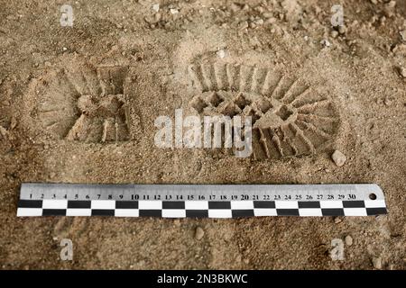 Ruler near footprint on sand, top view. Crime scene investigation and ...