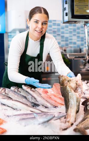 Positive saleswoman holding cod fish in fish store Stock Photo - Alamy