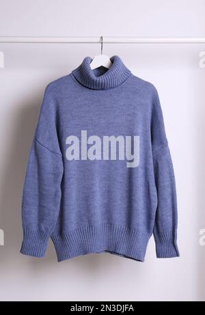 Warm sweater hanging on rack against white background Stock Photo - Alamy