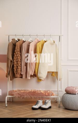 Rack with knitted sweaters in modern room Stock Photo - Alamy
