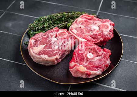 Raw Lamb Gerdan, lamb neck chops on a plate with herbs. Black ...