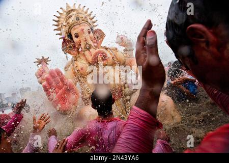 Indian Hindu devotees splash water on a large statue of the elephant ...