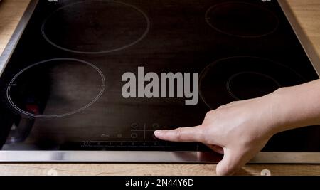 A woman's finger presses the inclusion of a modern induction hob in the ...