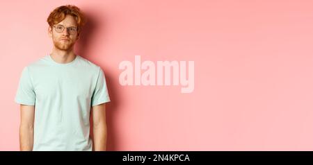 Sad and gloomy redhead bearded man in t-shirt and glasses, staring at ...