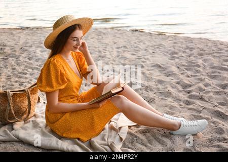Woman reading a book on the sandy beach in winter under beach umbrellas ...
