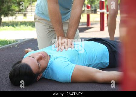 Passerby performing CPR on unconscious young man outdoors. First aid ...
