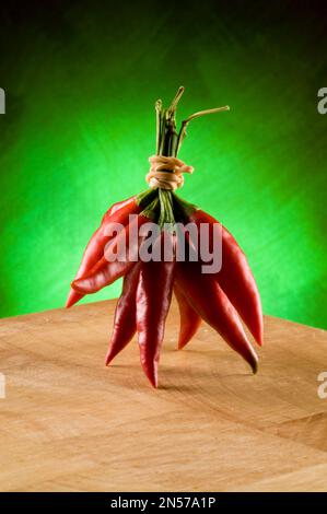 Bunch of red chilli peppers sitting on a timber bench Stock Photo - Alamy