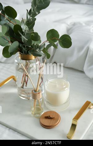 Eucalyptus branches, candle and aromatic reed air freshener on bed ...