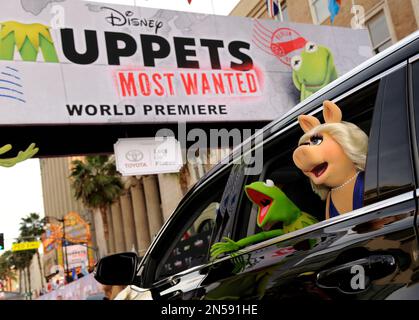 "Muppets Most Wanted" characters Kermit the Frog and Miss Piggy wave to the crowd as they arrive ...