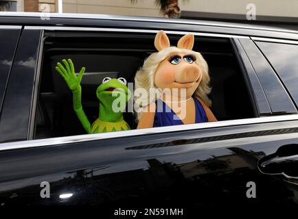 "Muppets Most Wanted" characters Kermit the Frog and Miss Piggy wave to the crowd as they arrive ...
