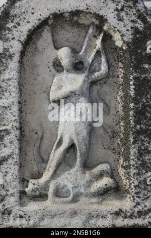A worn and weathered natural stone statue of Saint Michael the ...