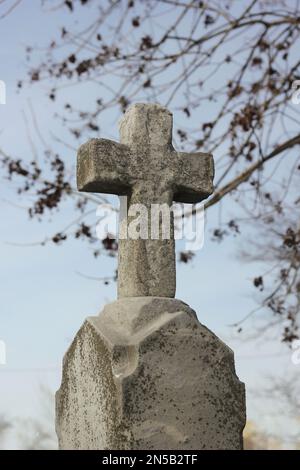 Simple vintage Christian cross standing high on a tombstone in the ...
