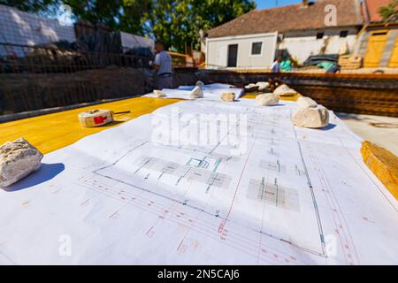 Architectural blueprints, drawings spread out on the improvised table ...
