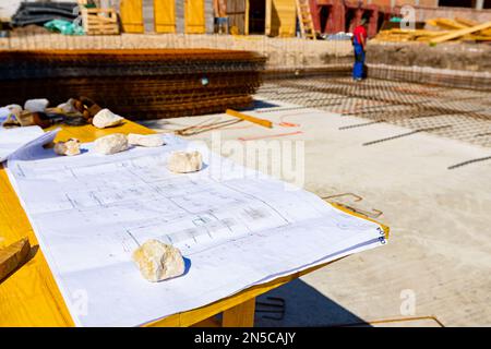 Architectural blueprints, drawings spread out on the improvised table ...