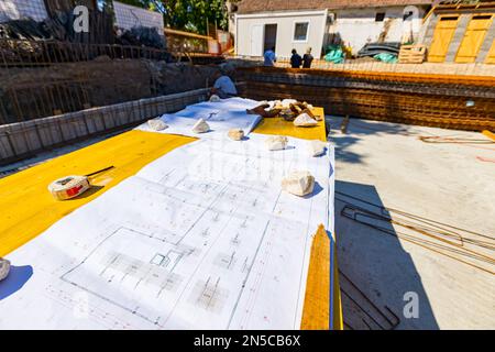 Architectural blueprints, drawings spread out on the improvised table ...