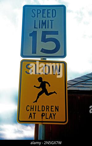 The signs of speed limit and slow, children at play on metal pole at ...