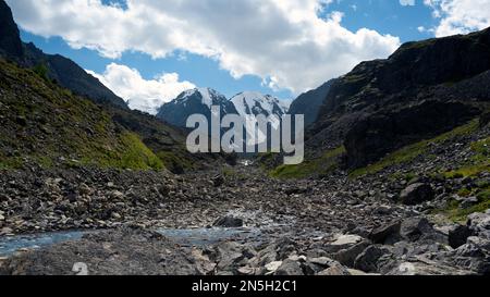 Alpine stream quickly flows under stones from high mountains with ...